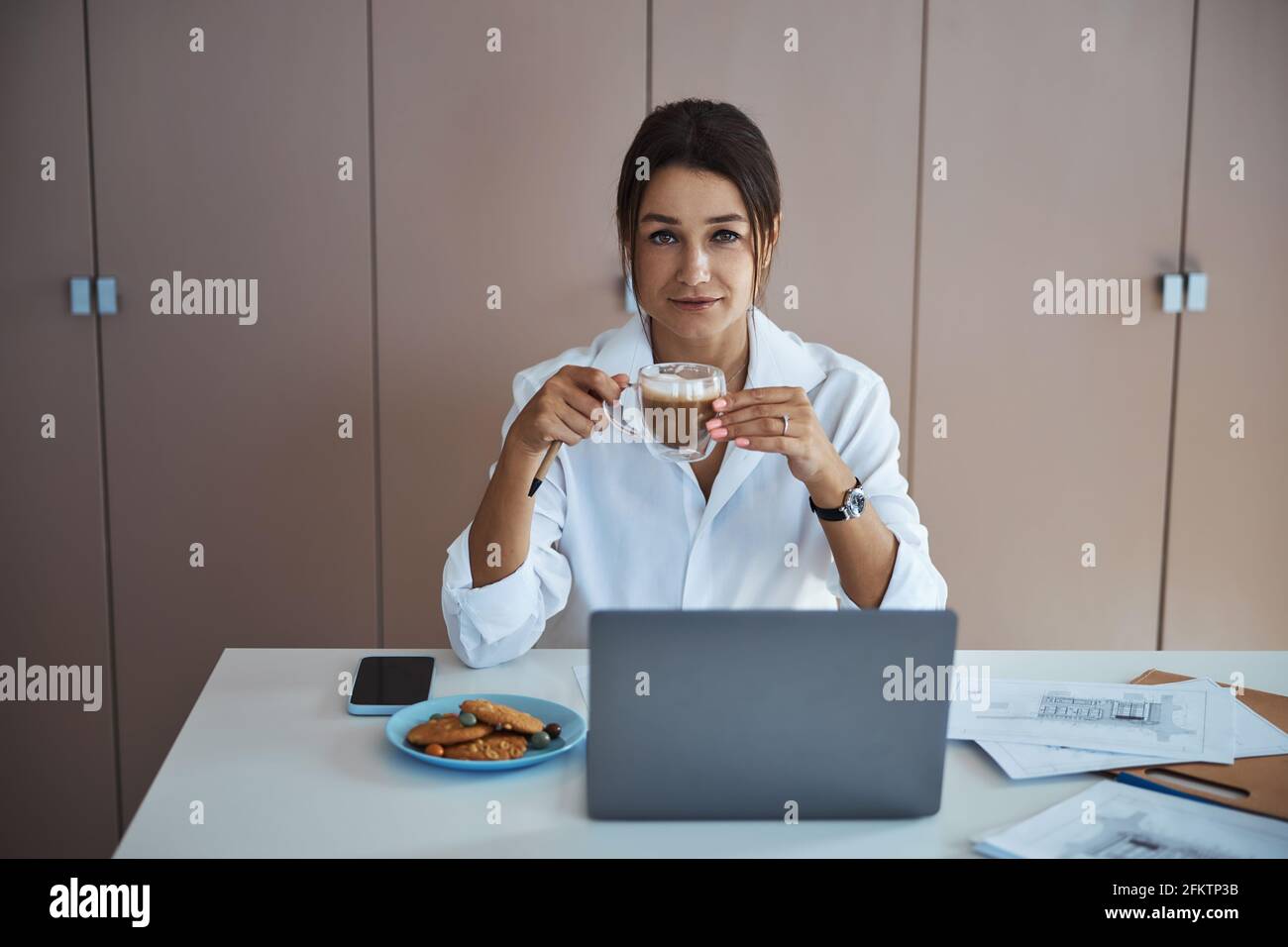 Charming young woman drinking latte at work Stock Photo - Alamy
