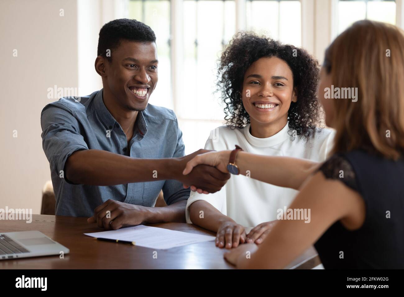 Happy young african american clients shaking hands with financial ...
