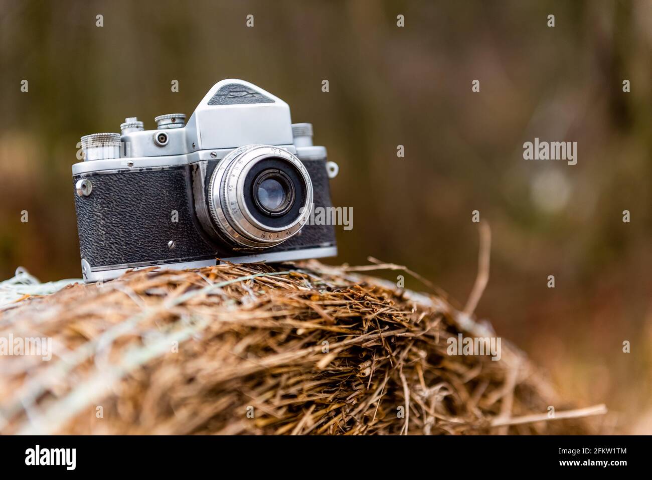 old film camera laying on a stack of hay, natural background ...
