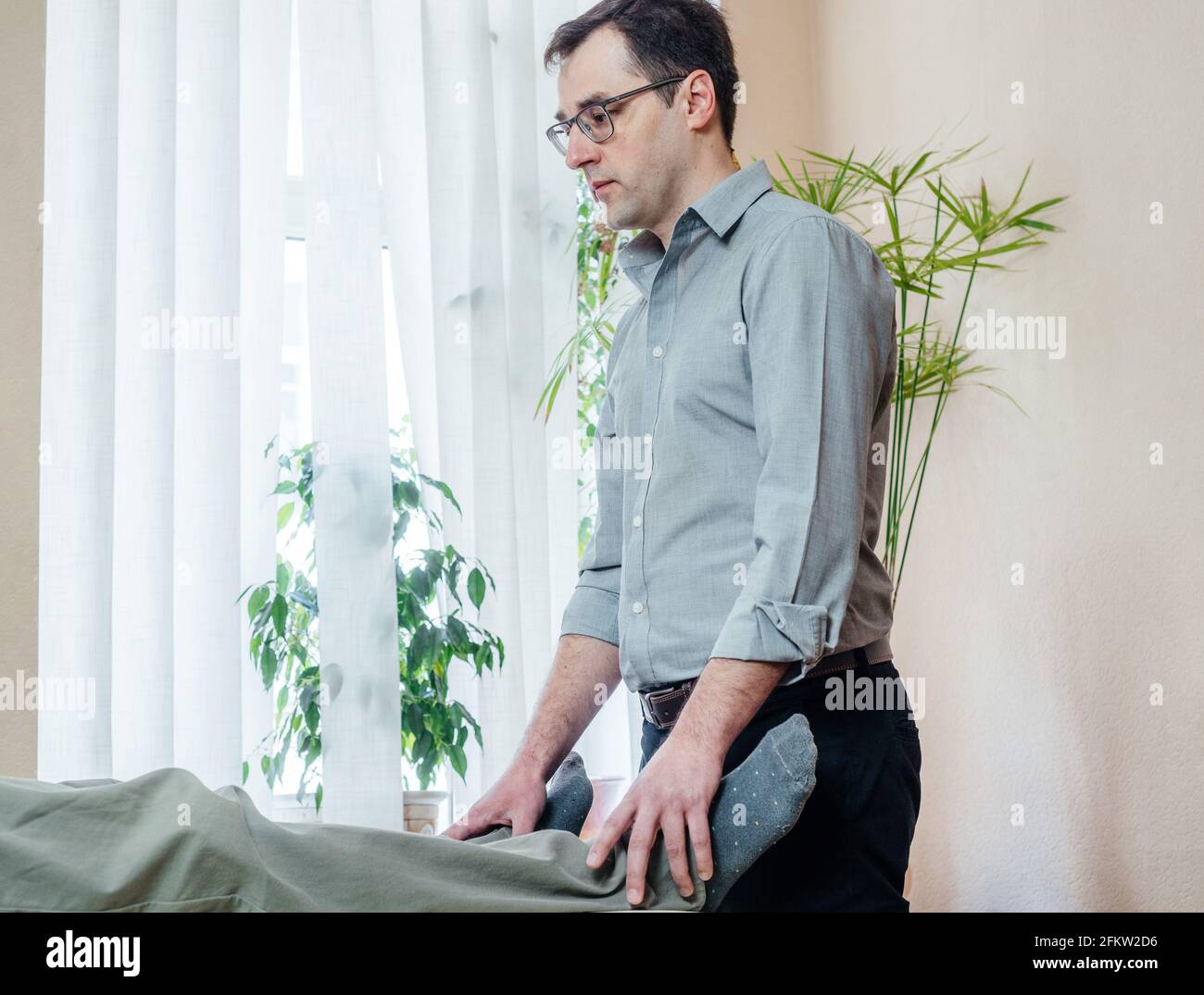 Craniosacral therapy practitioner giving a male patient CST osteopathic ...