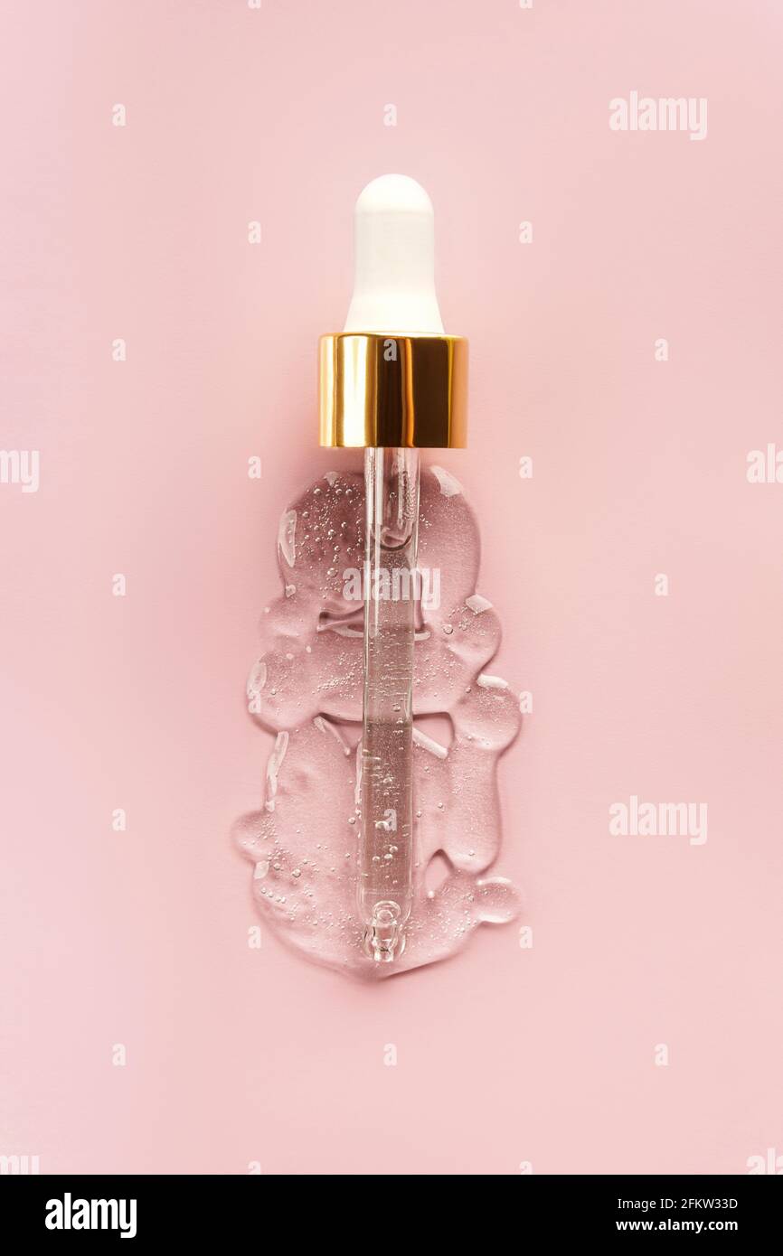 Liquid serum and dropper on a pink background top view. Serum drops in ...