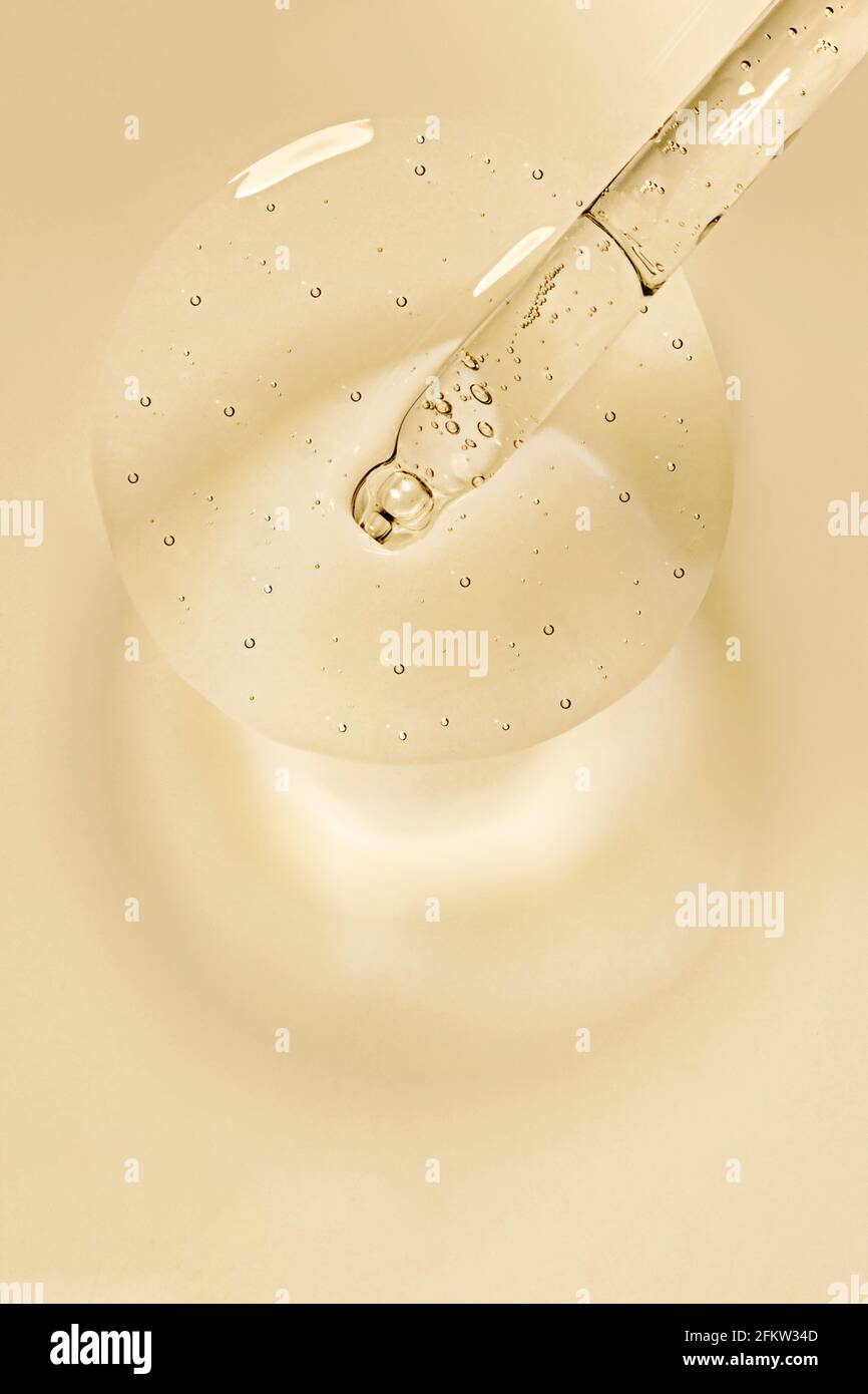 Liquid serum and dropper on a beige background top view. Serum drops in ...