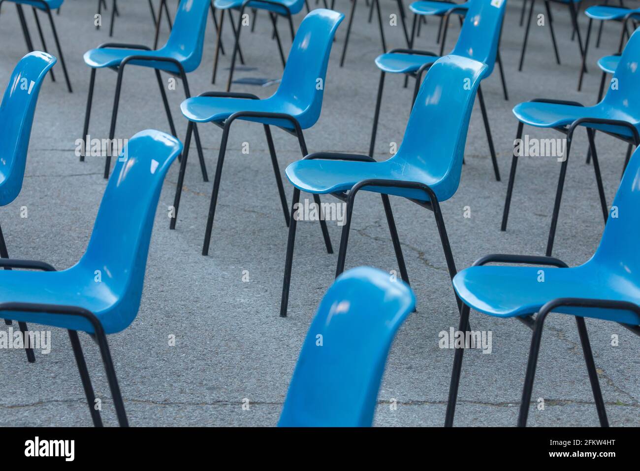 Rows and columns of nondescript blue plastic chairs, consecutive ...