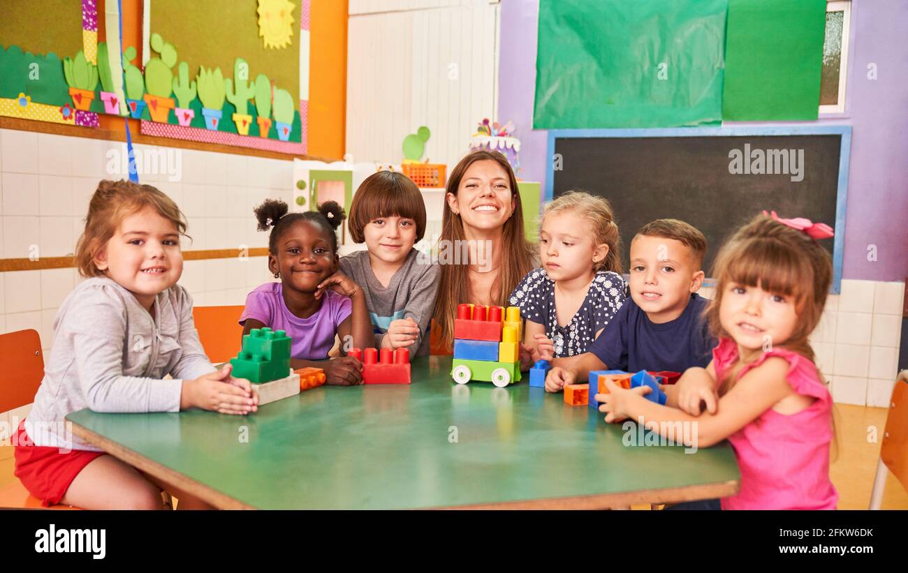 Happy kindergarten teacher and multicultural children in international ...