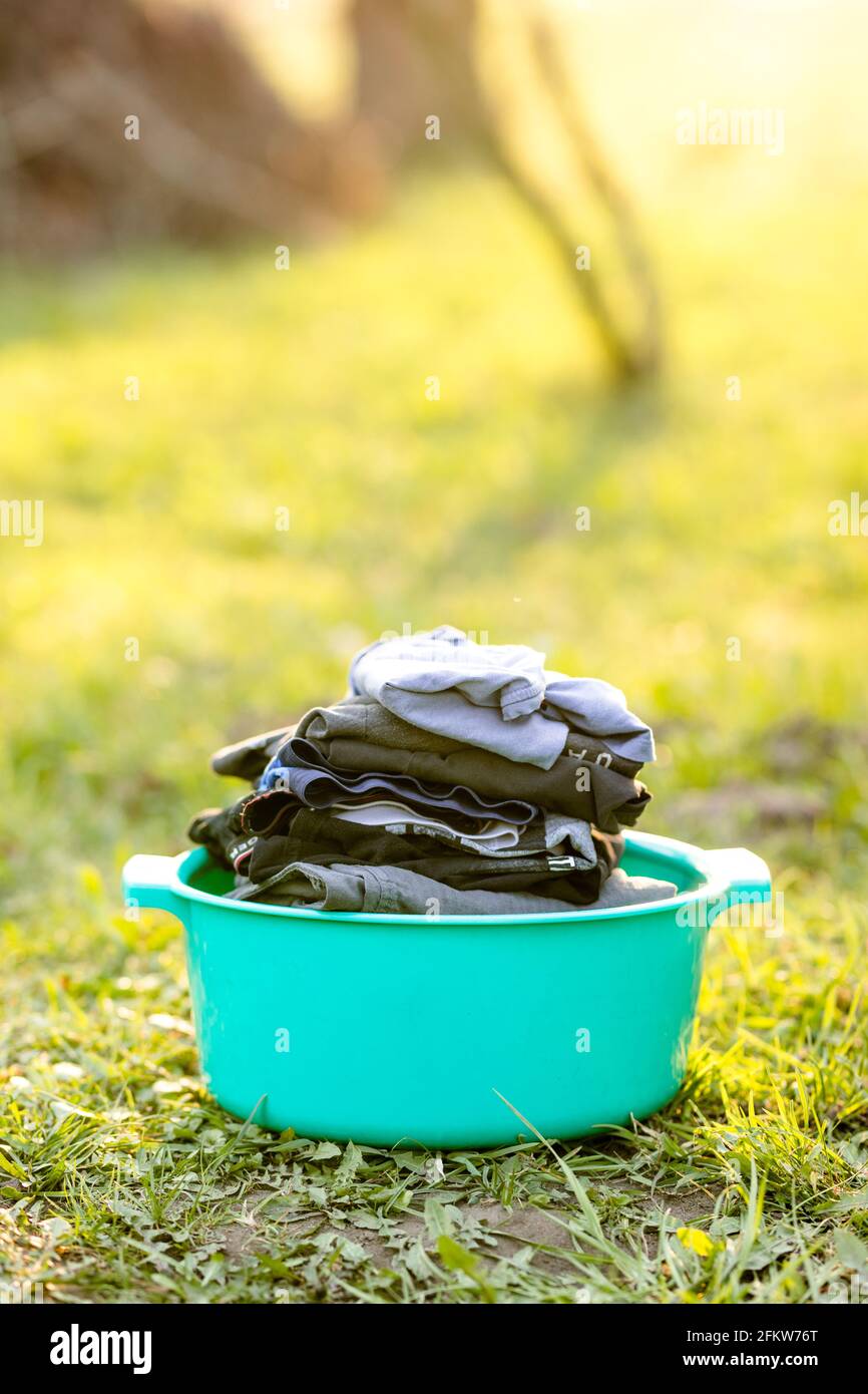 A blue laundry basket with dark folded clothes in spring Stock Photo ...