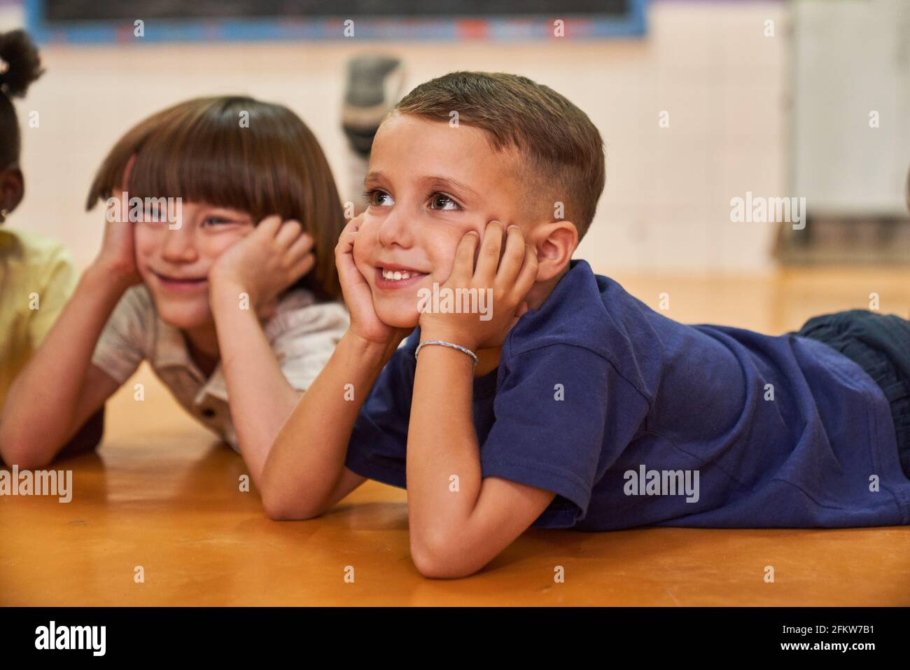 Two happy children as friends relax their heads on their hands in ...