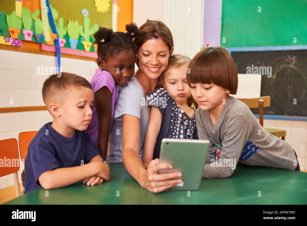 Educator with group of children makes selfie on tablet computer in ...