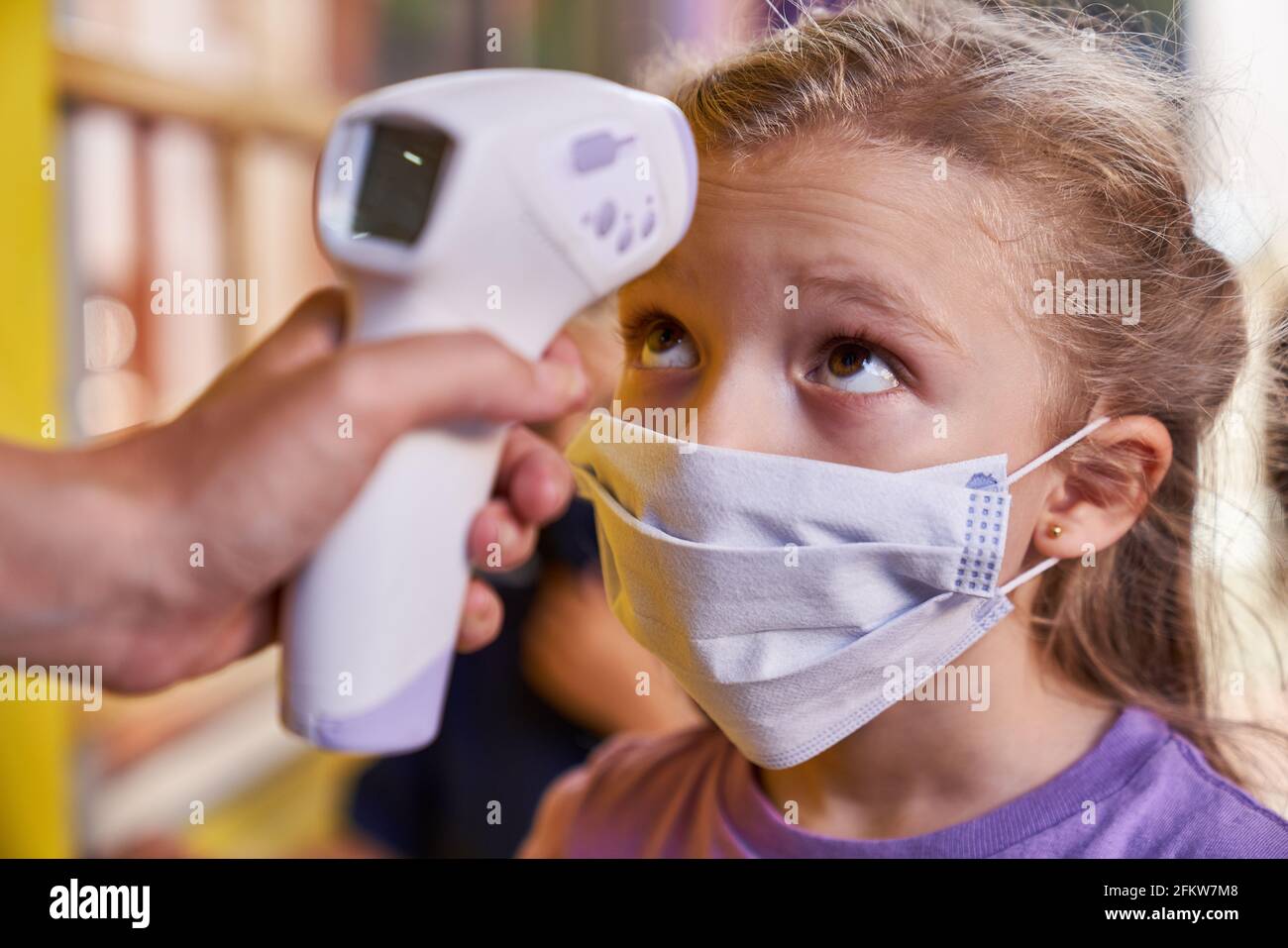 Child with a face mask during the fever measurement with the ...