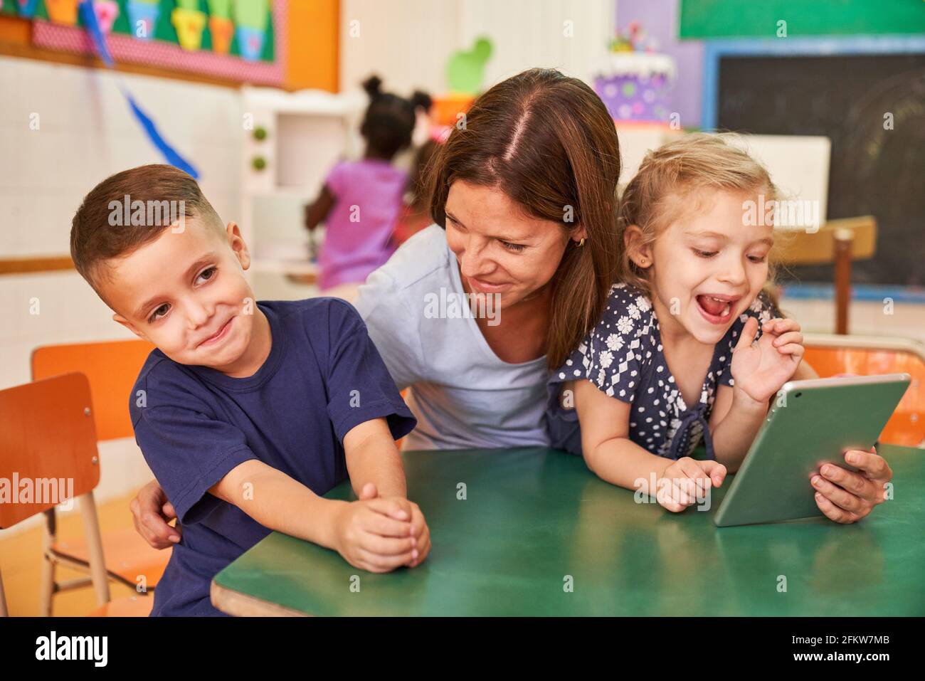 Kindergarten teacher has fun with children on tablet computers in ...