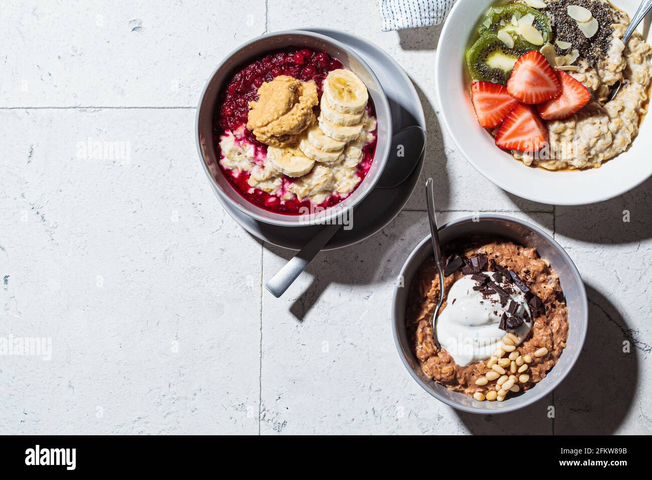 Assorted oatmeal bowls with chocolate, fruit and yogurt, gray tiles ...