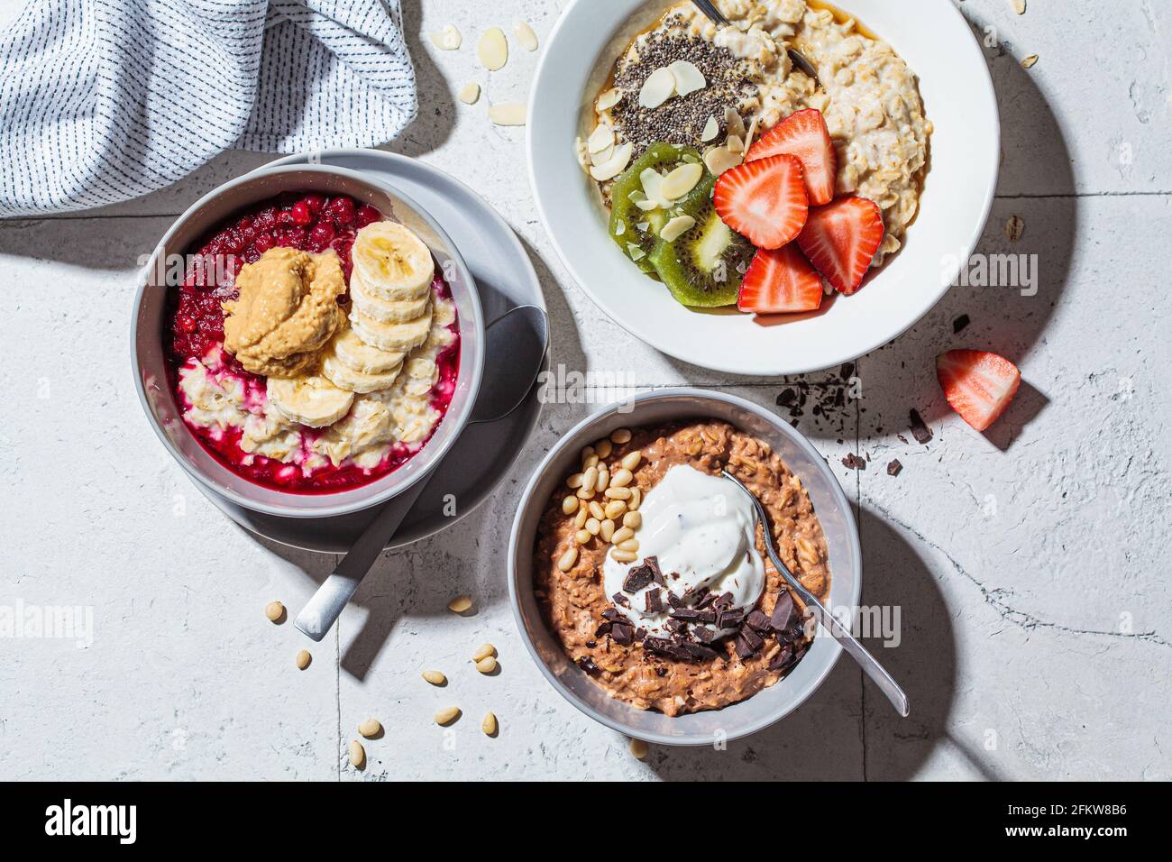 Assorted oatmeal bowls with chocolate, fruit and yogurt, gray tiles ...