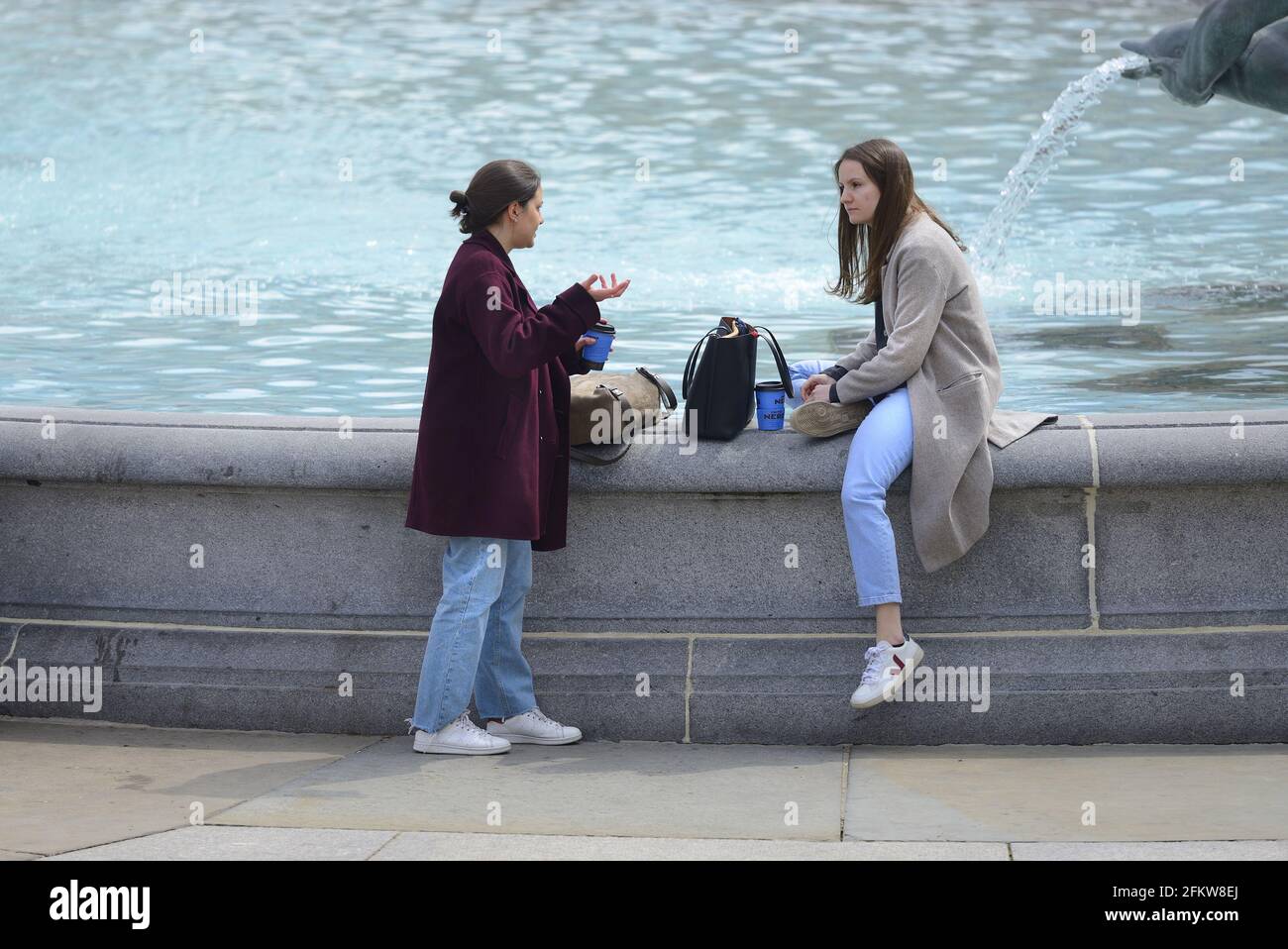 London, England, UK. Two young women talking by the fountain in ...