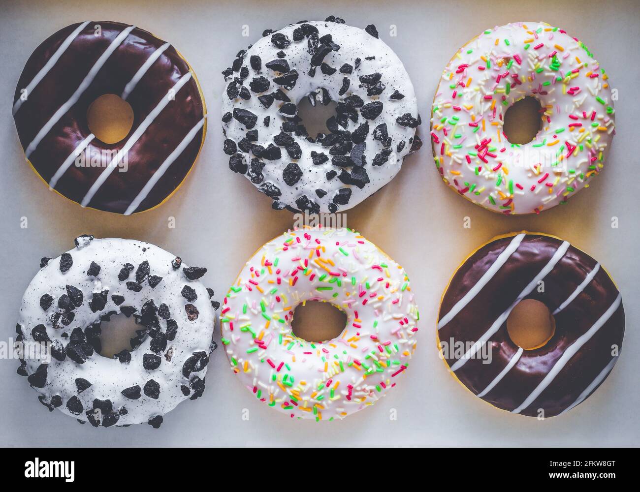 Flat lay image of six ring donuts with white glaze and colourful ...
