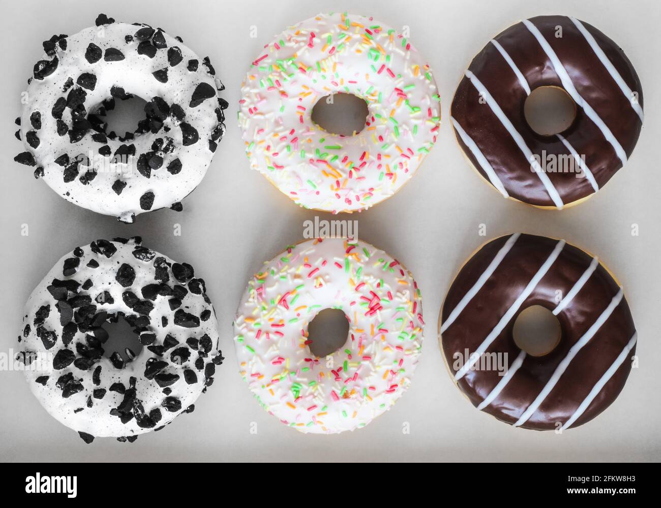 Flat lay image of six ring donuts with white glaze and colourful ...