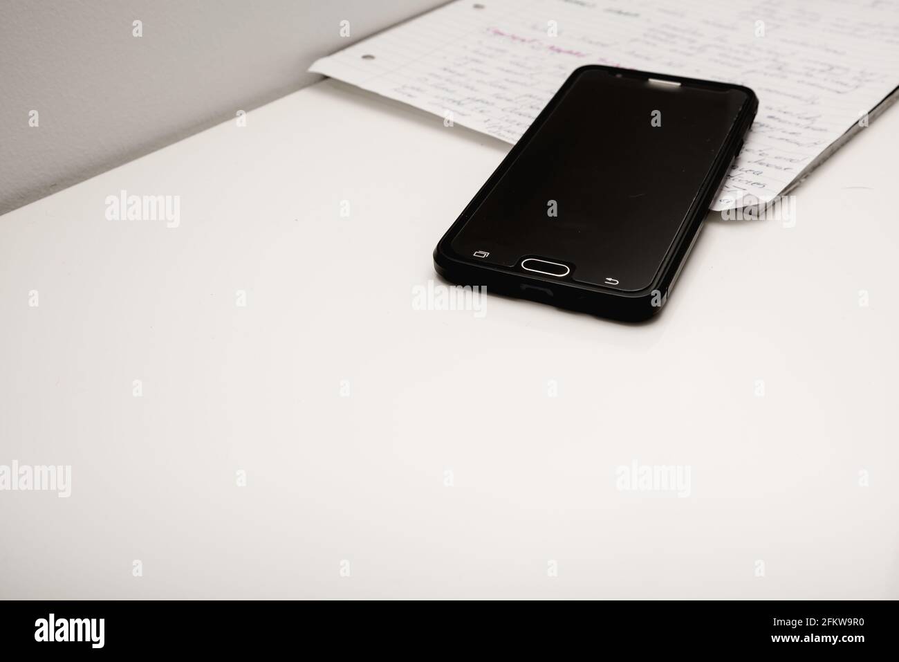 A stack of white sheets of paper, an open notebook, a mobile phone ...