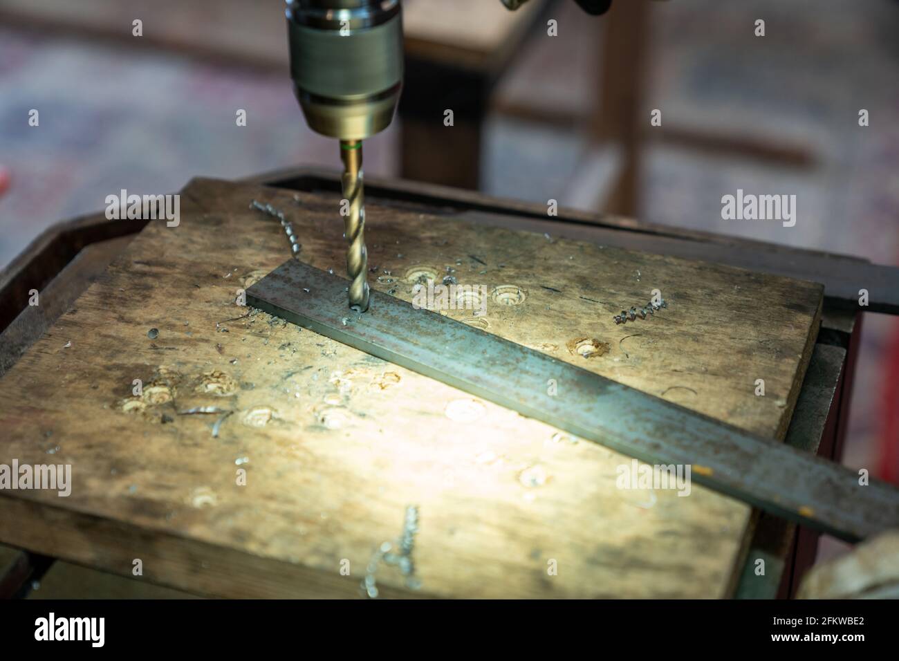 A close up of a bench drill drilling a hole into a metal sheet in a ...