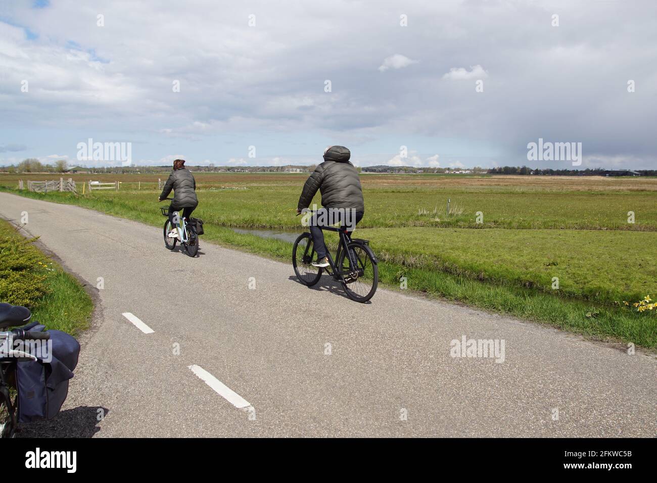 Dutch pasture landscape. Cyclists, who ride in the spring on a road ...