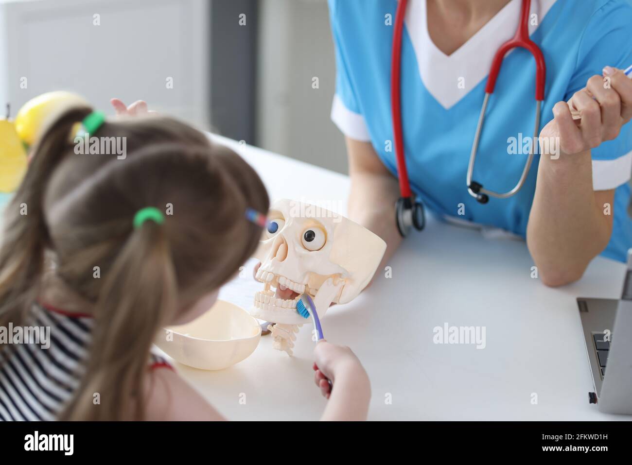Little girl together with dentist learns to properly brush her teeth on ...