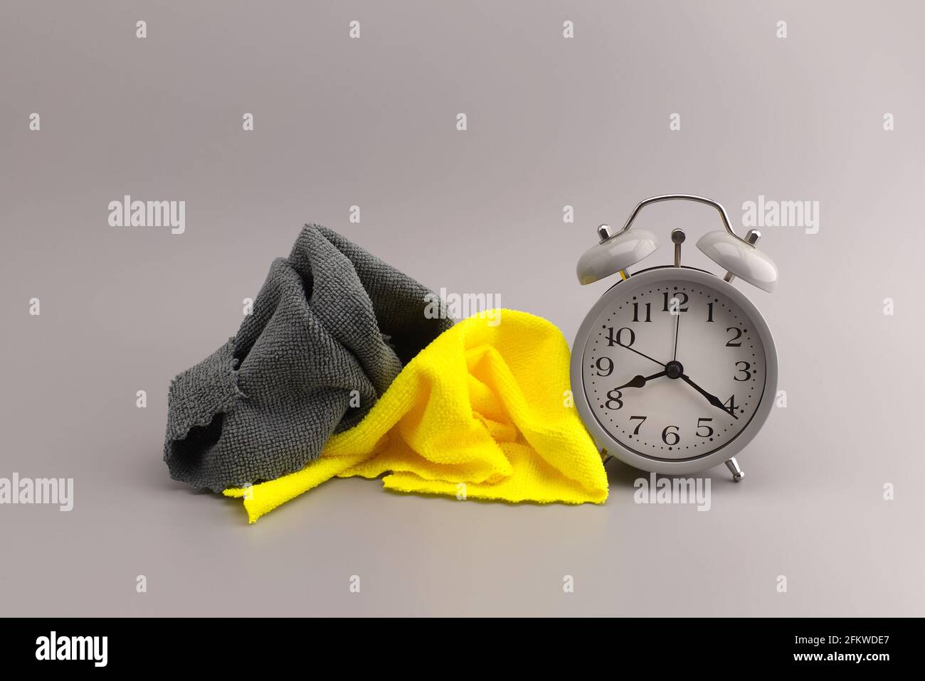 Gray vintage alarm clock near two tone grey and yellow textile cloth ...