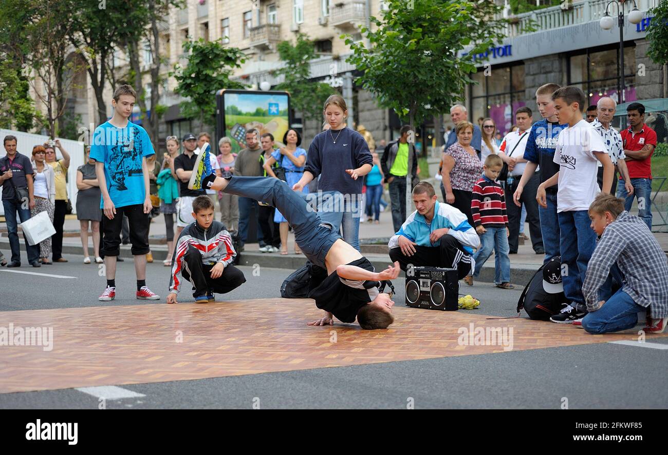 Young boy, street dancer, performimg break dance on the pavement ...