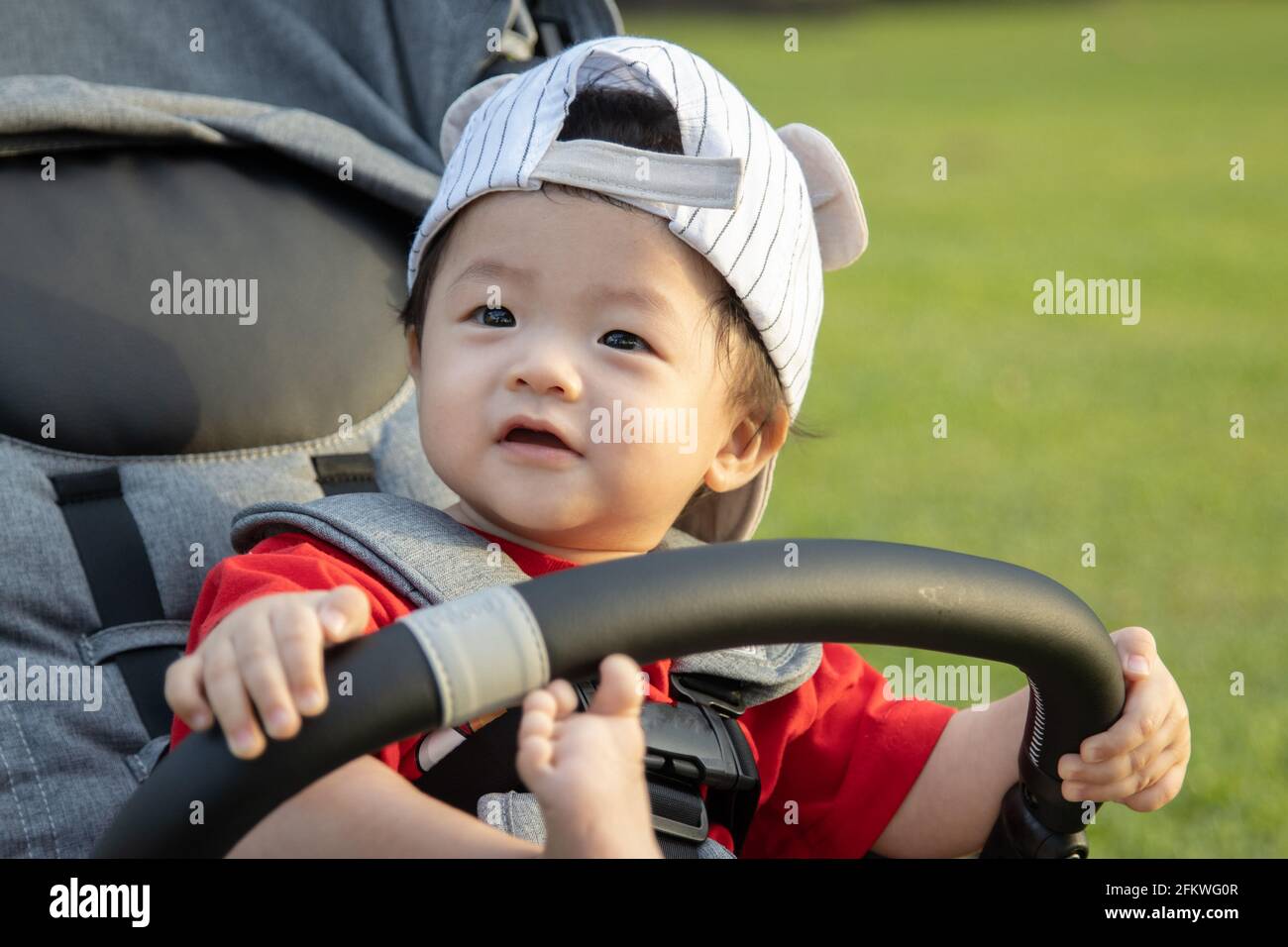 Happy and cute Asian Chinese baby boy sitting on stroller at park ...