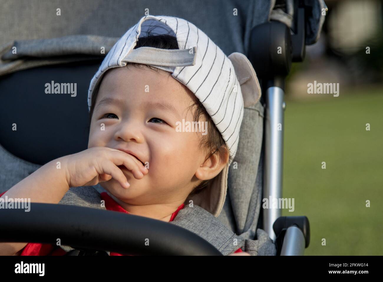 Happy and cute Asian Chinese baby boy sitting on stroller at park ...