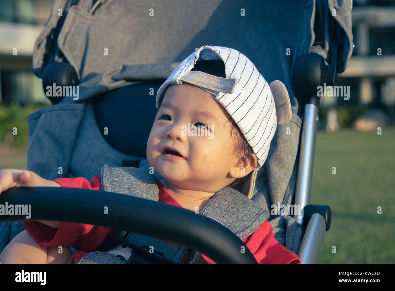 Happy and cute Asian Chinese baby boy sitting on stroller at park ...
