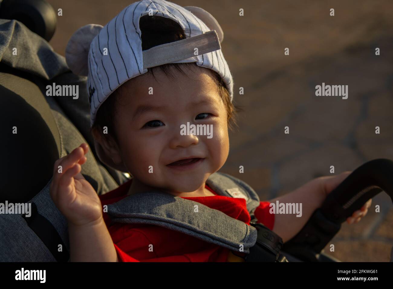 Happy and cute Asian Chinese baby boy sitting on stroller at park ...