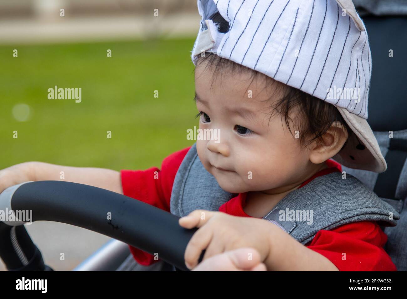 Happy and cute Asian Chinese baby boy sitting on stroller at park ...