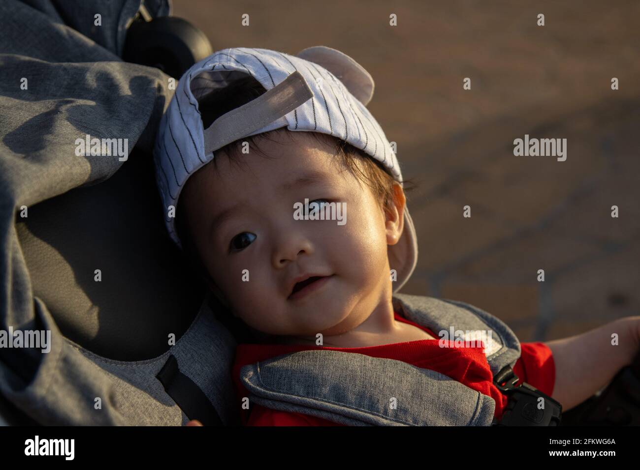 Happy and cute Asian Chinese baby boy sitting on stroller at park ...