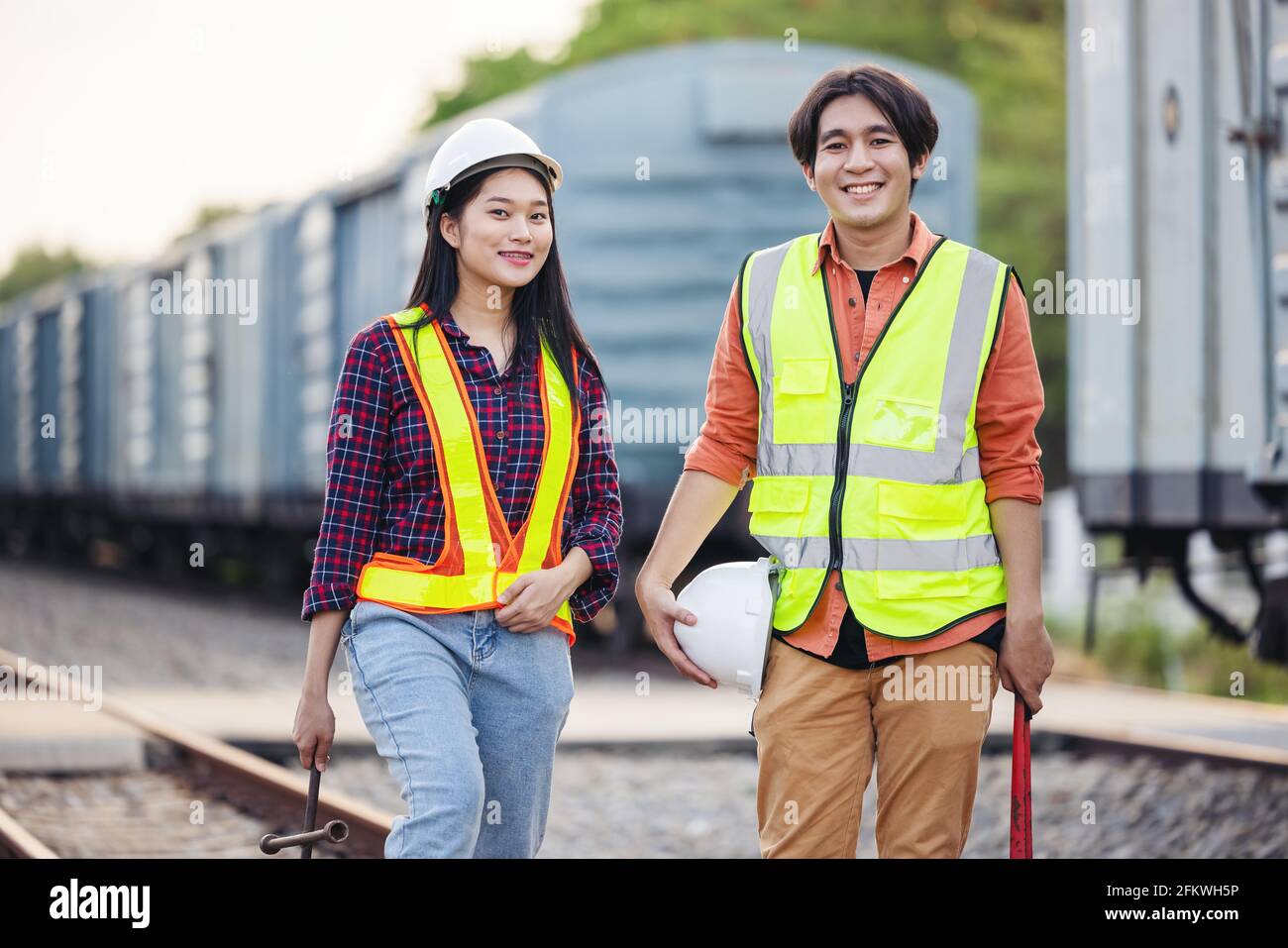 Maintenance technician in a safety suit stands beside a freight train ...