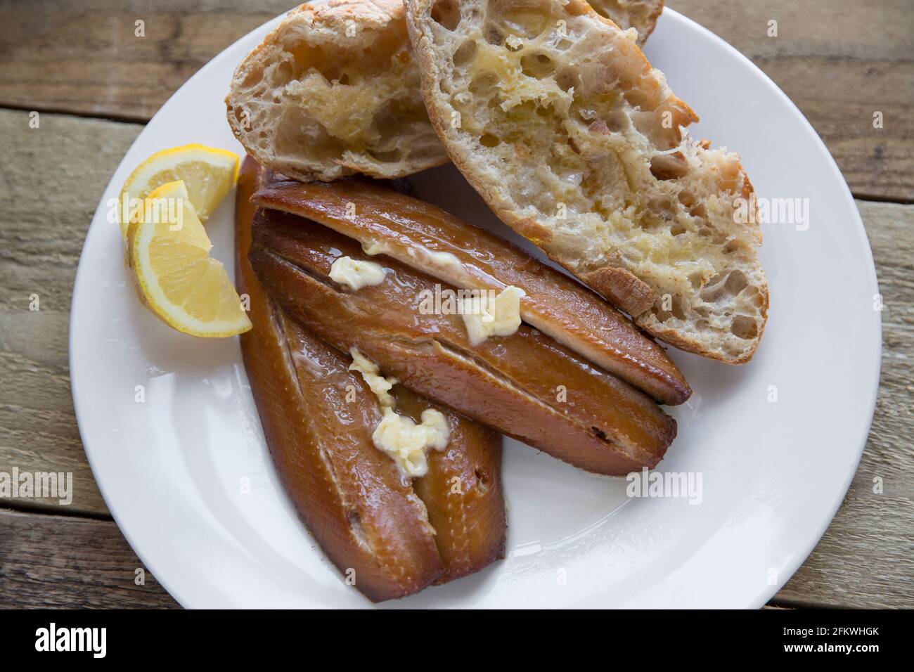 Smoked Craster kipper cutlets presented on a wooden background. Kippers ...