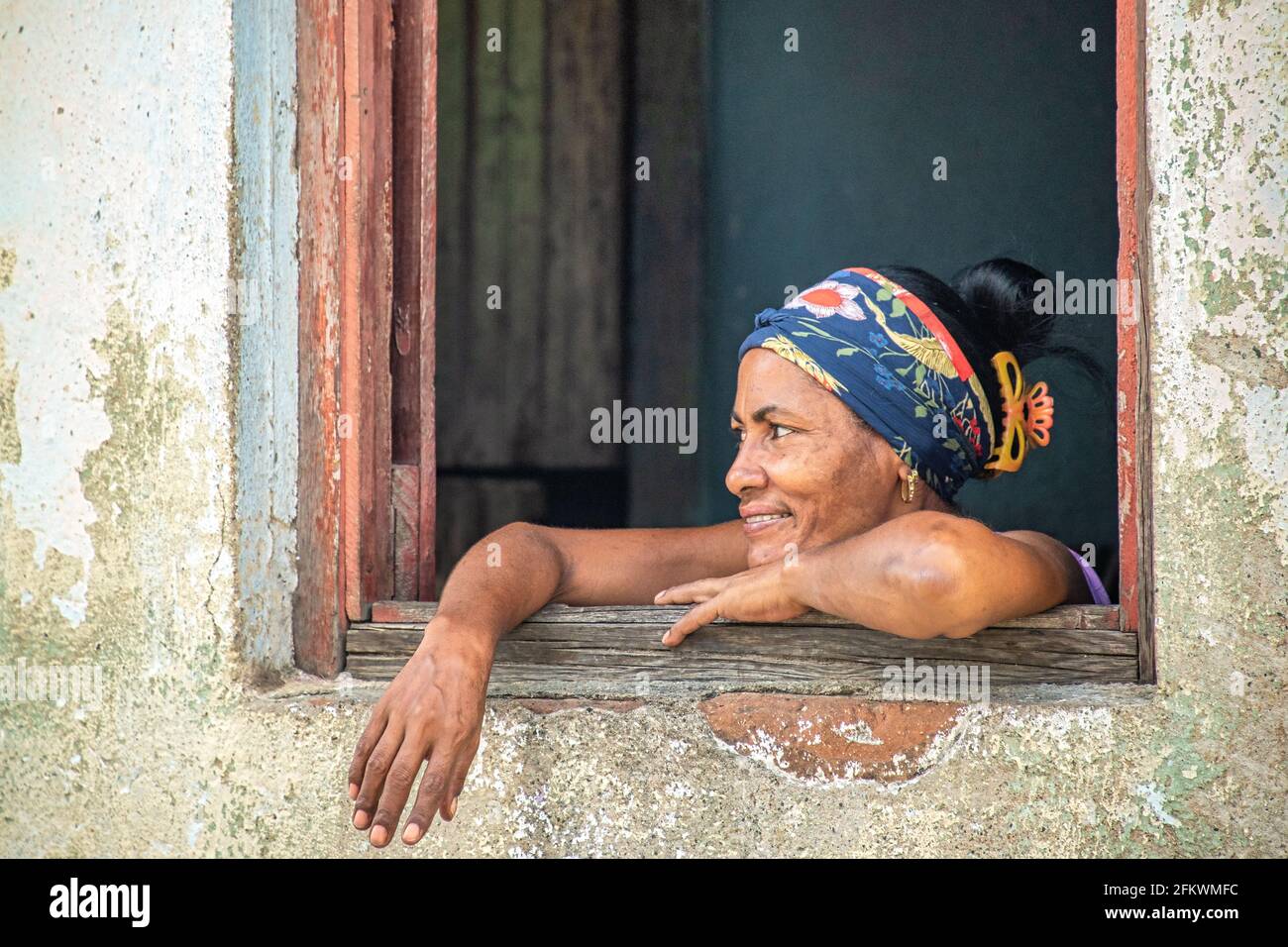 Portrait of Cuban woman in a window of a weathered house, Cuba. Year ...
