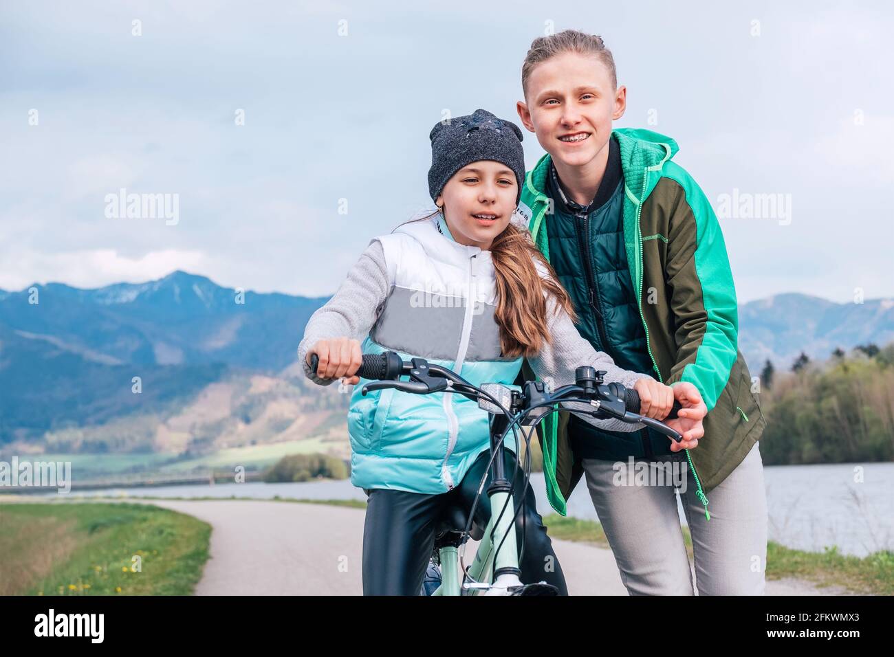 Brother helping to sister and teaching doing first steps in riding ...