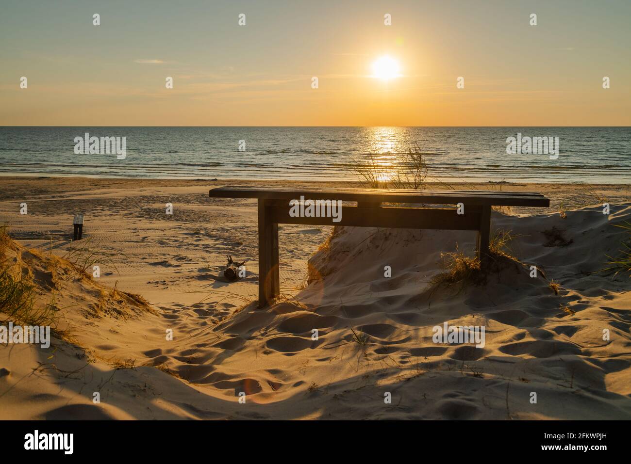 Empty wooden bench and beautiful golden sunset at the beach. Sun ...