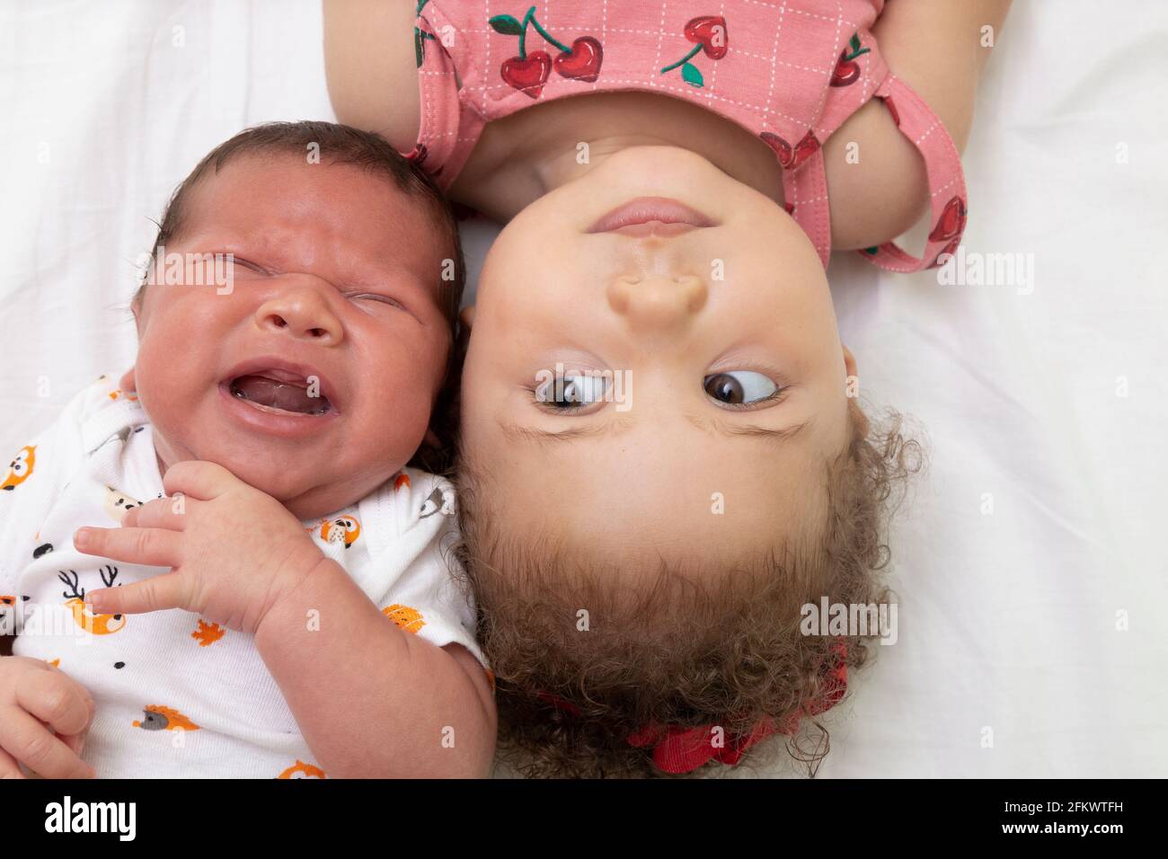 1 year old girl looking at crying brother next to her Stock Photo - Alamy