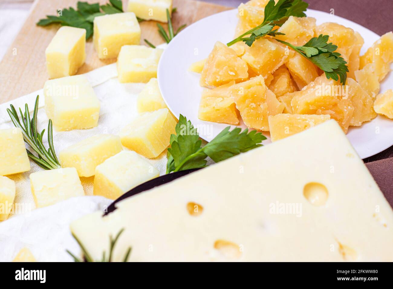 Variety of parmesan and maasdam pieces cheese in the kitchen on light ...