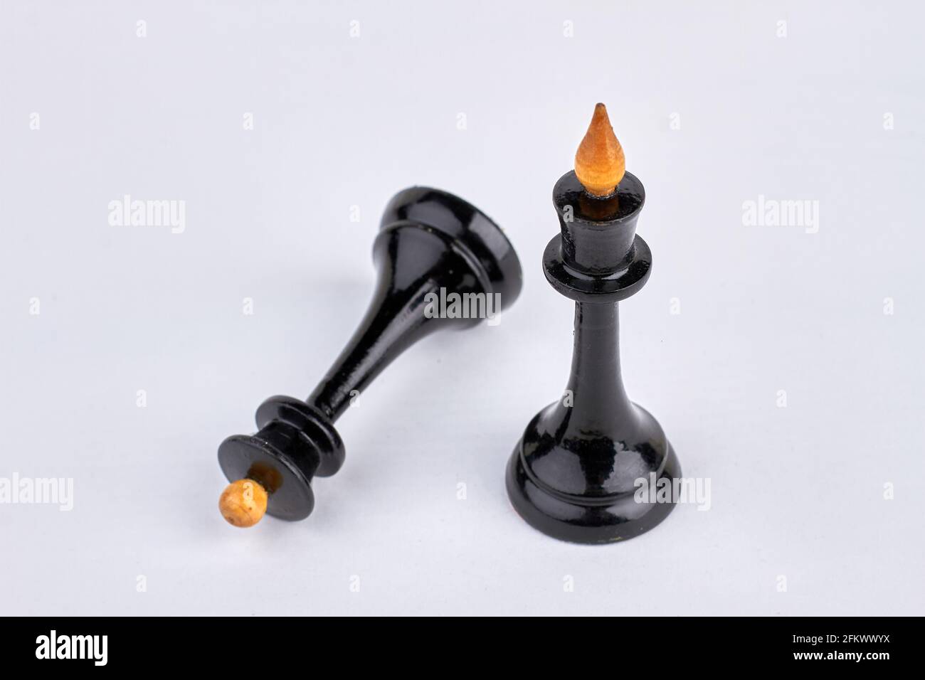 Black queen chess piece stands near fallen chess piece Stock Photo - Alamy