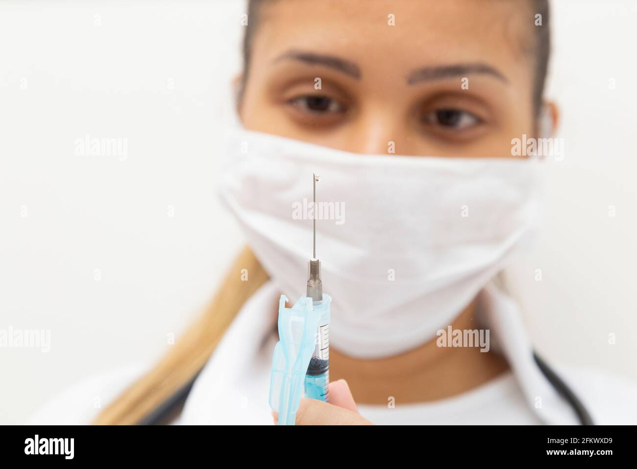 Female doctor looking at a drop on the tip of the syringe needle Stock ...