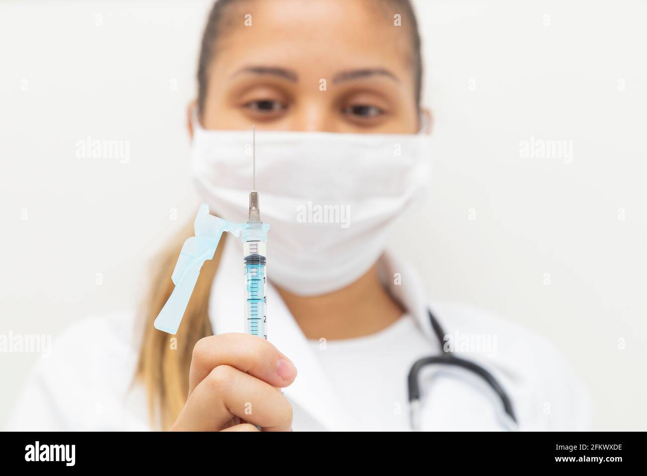 Female doctor staring at the needle of a syringe with vaccine Stock ...