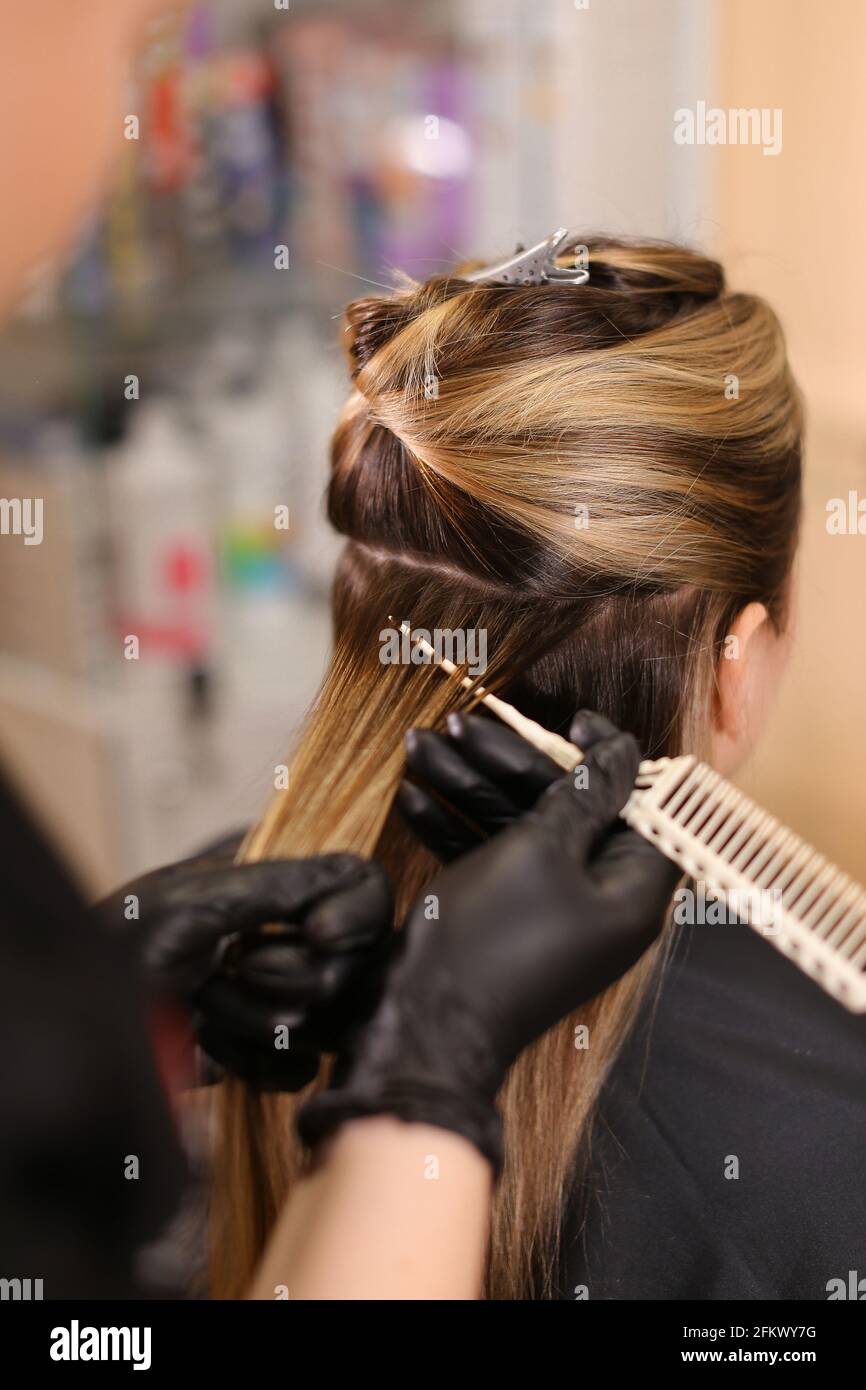 Professional female hairdresser applying color to female customer at ...