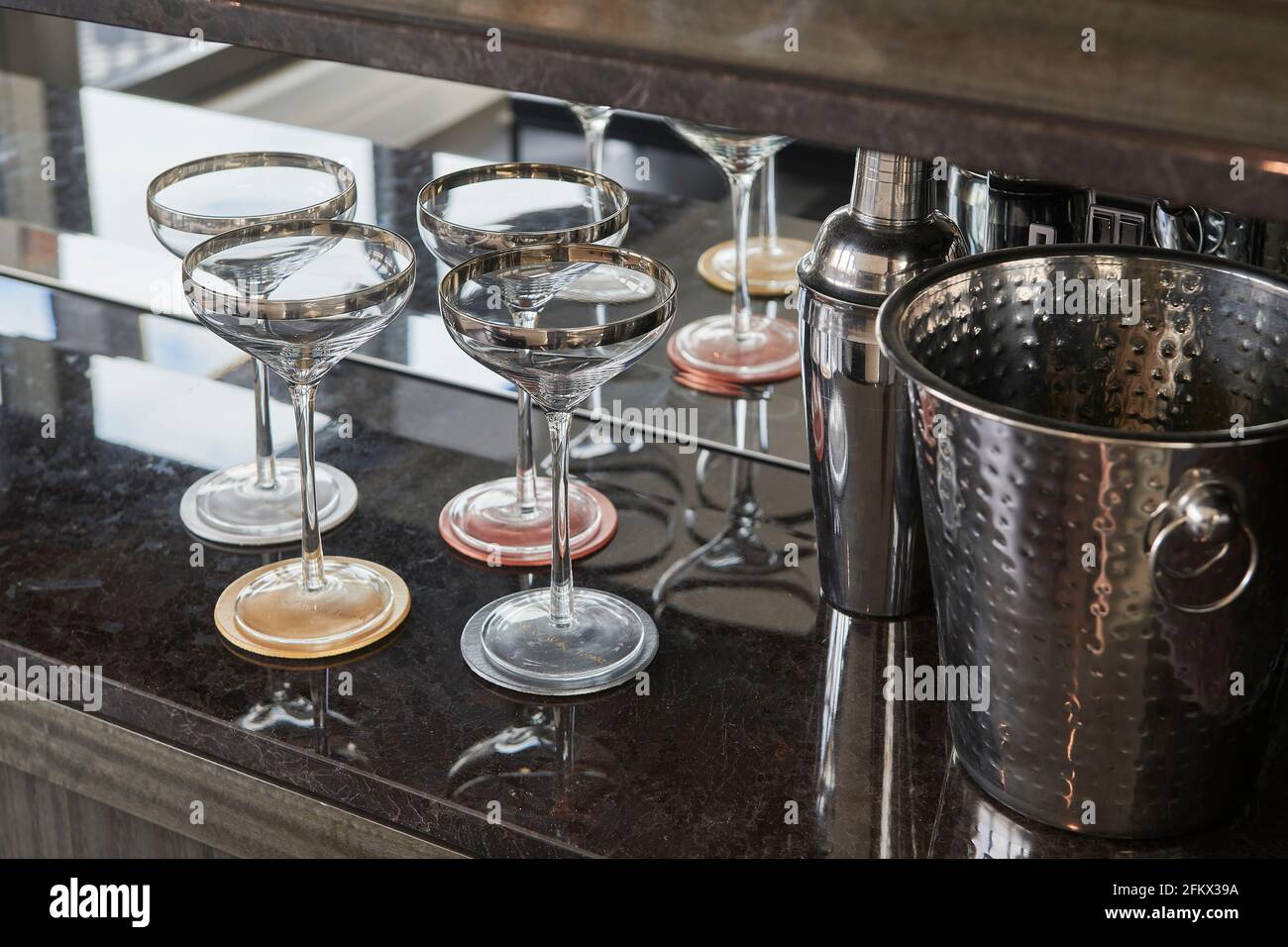 Cocktail glasses, a shaker and an ice bucket on the top of a drinks ...