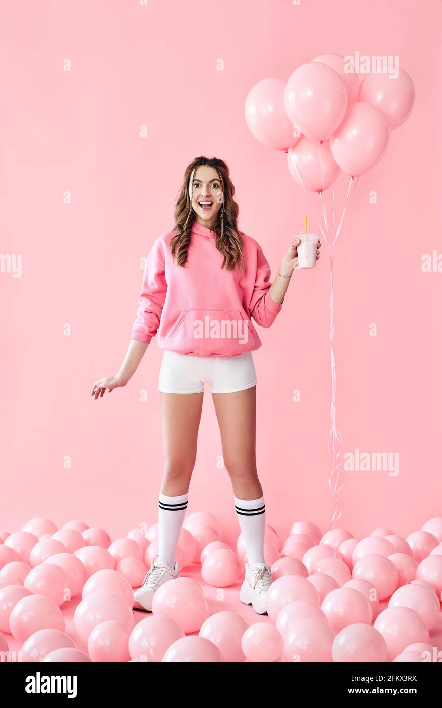 Full length portrait of trendy young woman with milk shake over pink ...