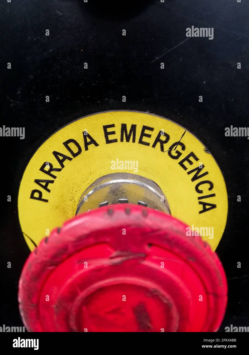 Red and yellow emergency stop button on black background with a sign in ...