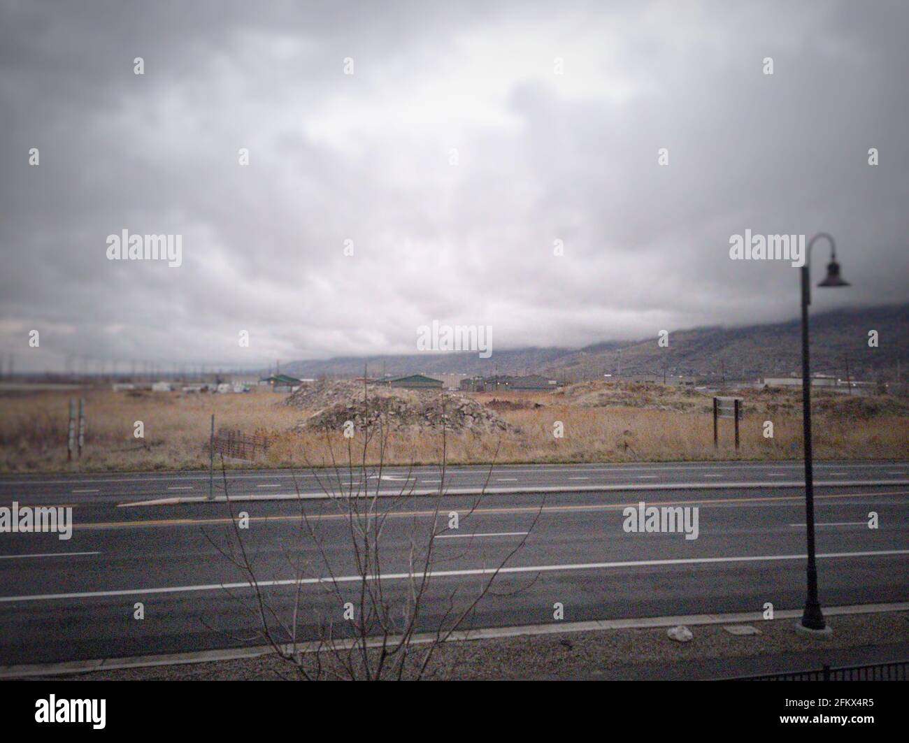 A side view of an empty wide street through dry autumn fields on a ...