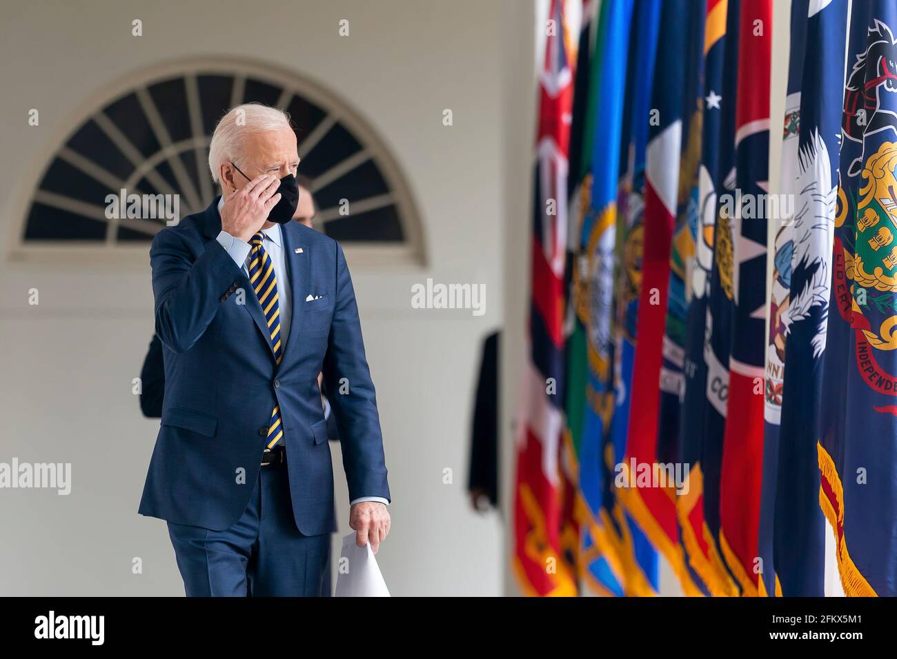 President Joe Biden salutes as he walks along the Colonnade of the ...