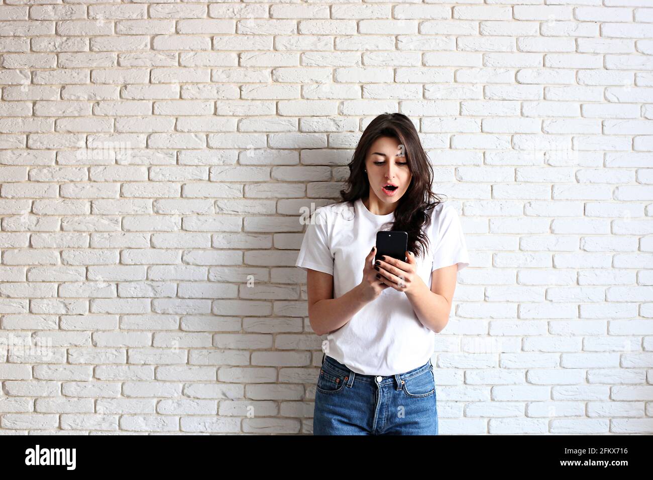 Young attractive woman in blank white shirt received surprise message ...