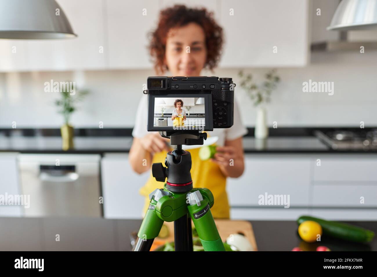 Woman youtuber records herself with a camera in the kitchen of her ...
