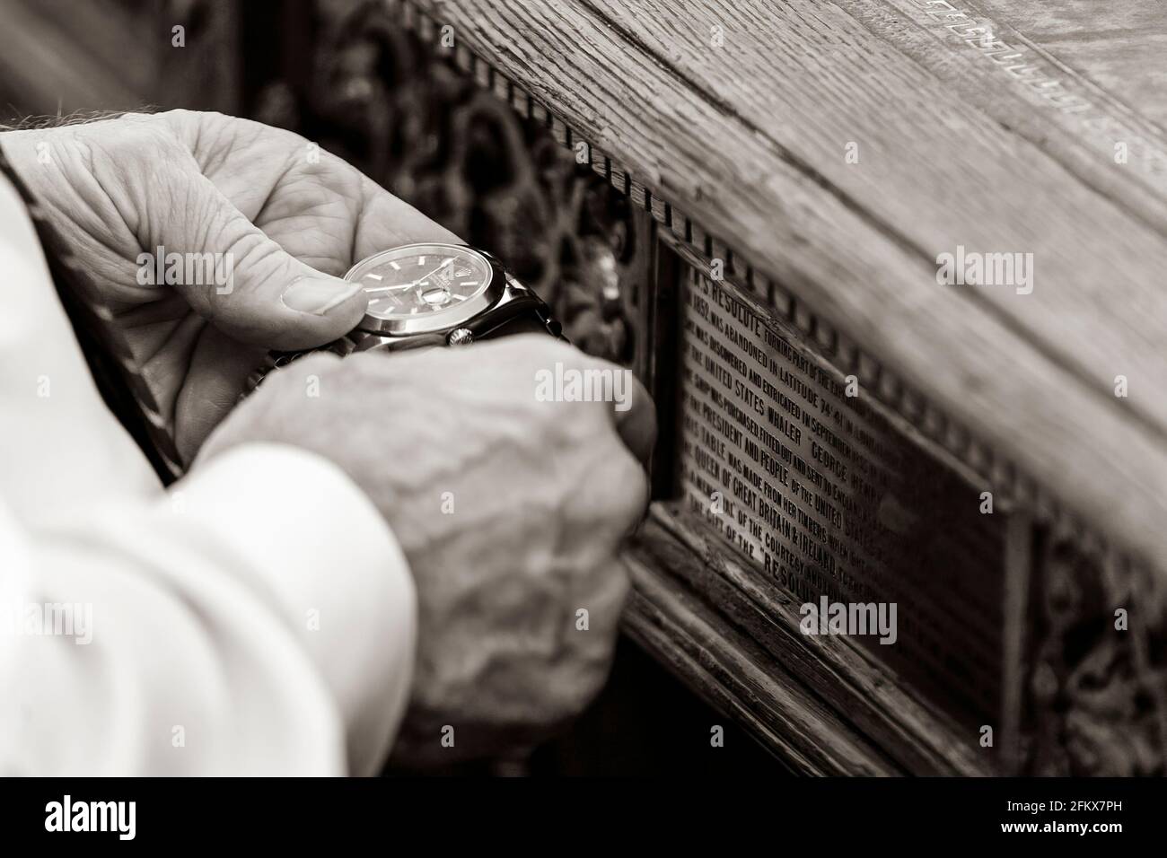 President Joe Biden checks the time on his watch as he sits at the ...