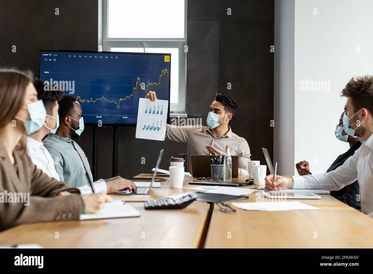 Man in protective medical mask showing paper with graph diagram Stock ...